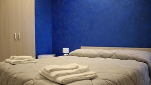Quarto com cama, mesa de cabeceira e parede com desenho de estrelas.