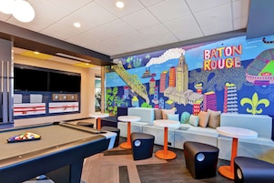 Espaço com mesa de bilhar e um mural vibrante de Nova Orleans, incluindo o nome 'BATON ROUGE'.