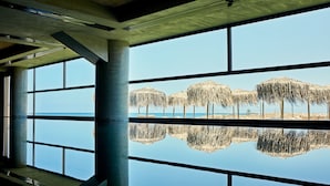 Interior moderno com grandes janelas refletindo uma cena de praia.