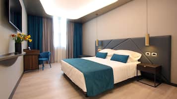 Quarto de hotel moderno com uma cama grande, uma escrivaninha com cadeira, TV de tela plana e um vaso com flores.
