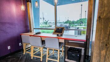 Espaço de escritório moderno com uma mesa, duas cadeiras, um computador e vista para o exterior.