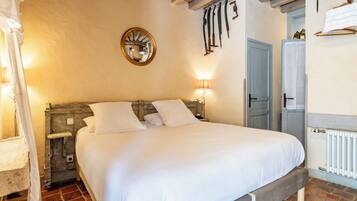 Quarto com uma cama grande, cabeceira de madeira, espelho redondo e luminária fixada na parede.