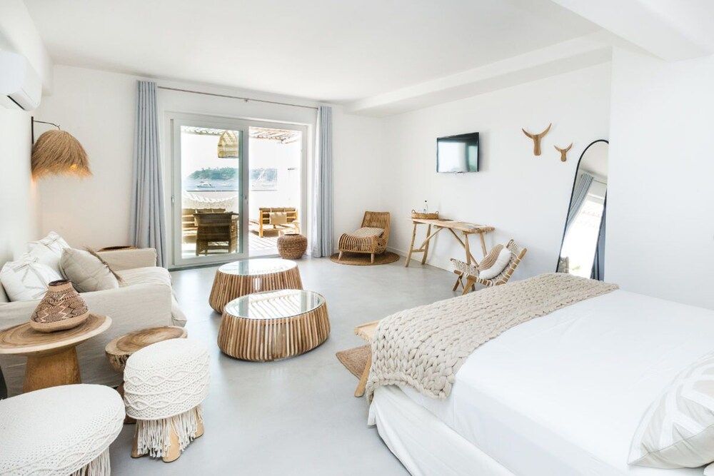 Um quarto de hotel espaçoso com uma cama grande, um sofá, uma mesa de jantar e uma área de estar com cadeiras.