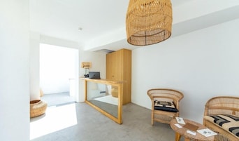 Quarto moderno com escrivaninha de madeira, mobiliário de vime e luminária pendente.