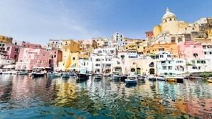 Uma cidade costeira com edifícios coloridos e barcos atracados à beira-mar.