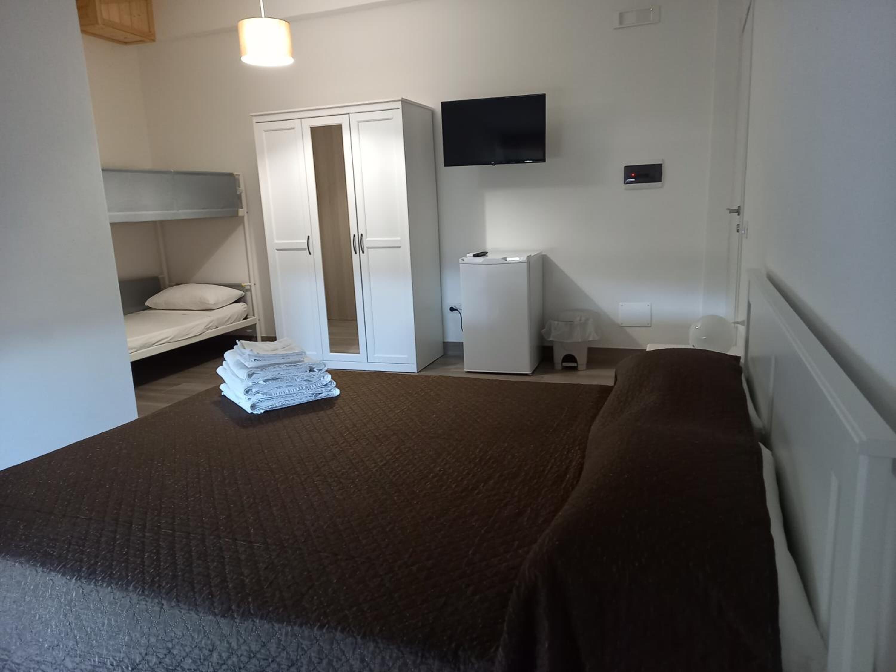 Quarto com beliche, guarda-roupa, televisão e frigorífico.