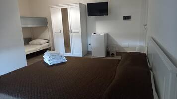 Quarto com beliche, guarda-roupa, televisão e frigorífico.