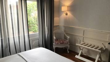 Um quarto com cama, poltrona, mesa de cabeceira e luminária na parede.