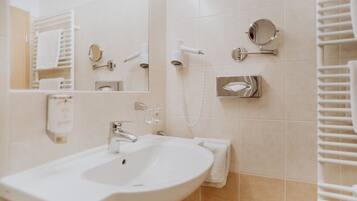 Casa de banho moderna com lavatório branco, porta-toalhas, espelho e secador de cabelo.