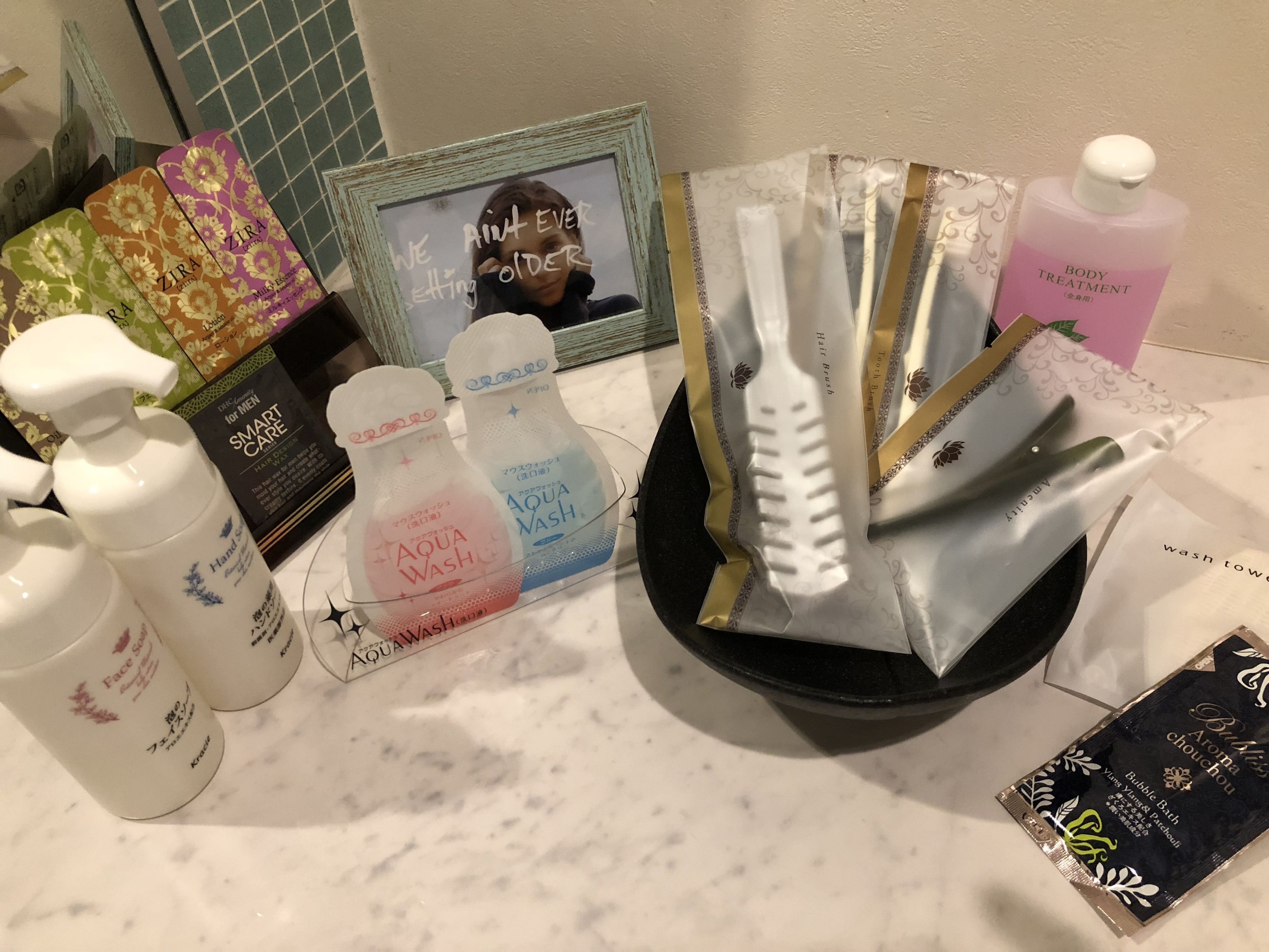 Uma bancada de banheiro com diversos produtos de higiene pessoal, incluindo sabonete líquido, shampoo e gel de banho.
