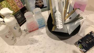 Uma bancada de banheiro com diversos produtos de higiene pessoal, incluindo sabonete líquido, shampoo e gel de banho.