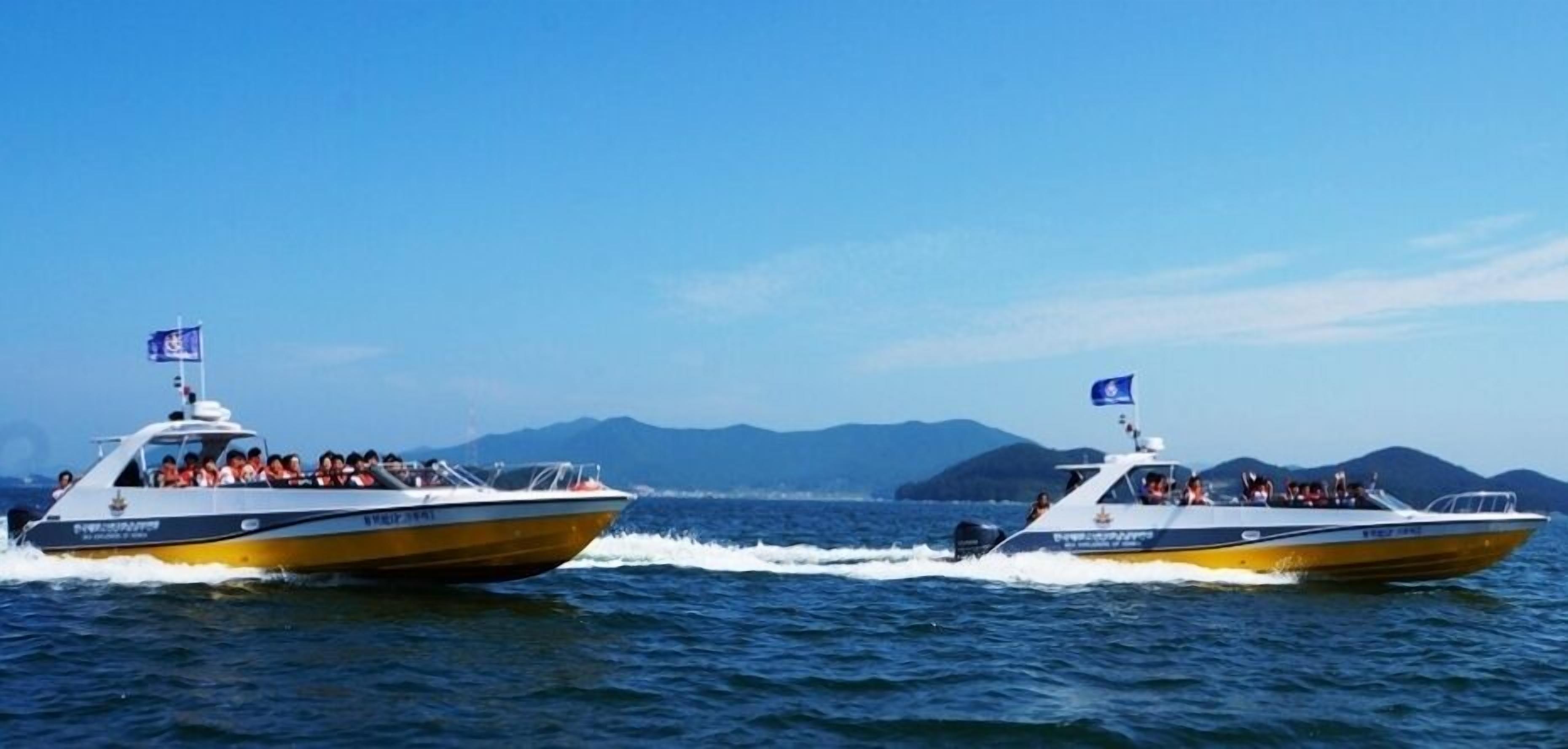 Dois barcos velozes em um corpo d'água, com montanhas ao fundo.