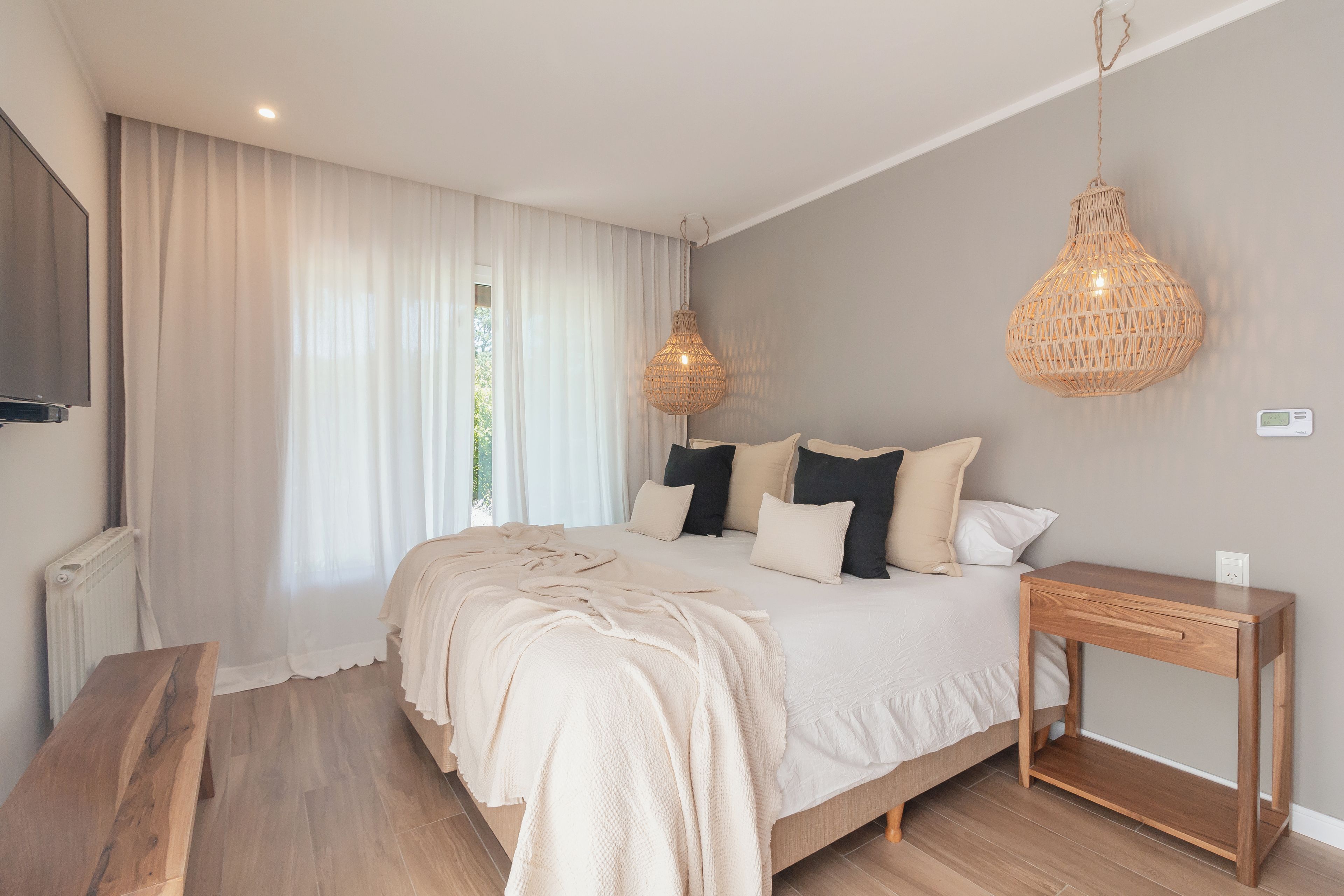 Quarto com cama, mesa de cabeceira e luminária suspensa.