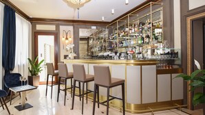 Uma área de bar com balcão, banquetas e diversos frascos e copos.