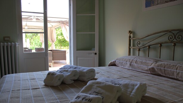 Cama bem arrumada com colcha listrada e várias toalhas dobradas com texto.