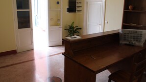 Quarto com uma escrivaninha de madeira, uma planta em vaso e uma porta branca.