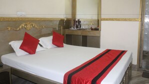 Quarto de hotel com cama, espelho, mesa de cabeceira e bancada no banheiro.