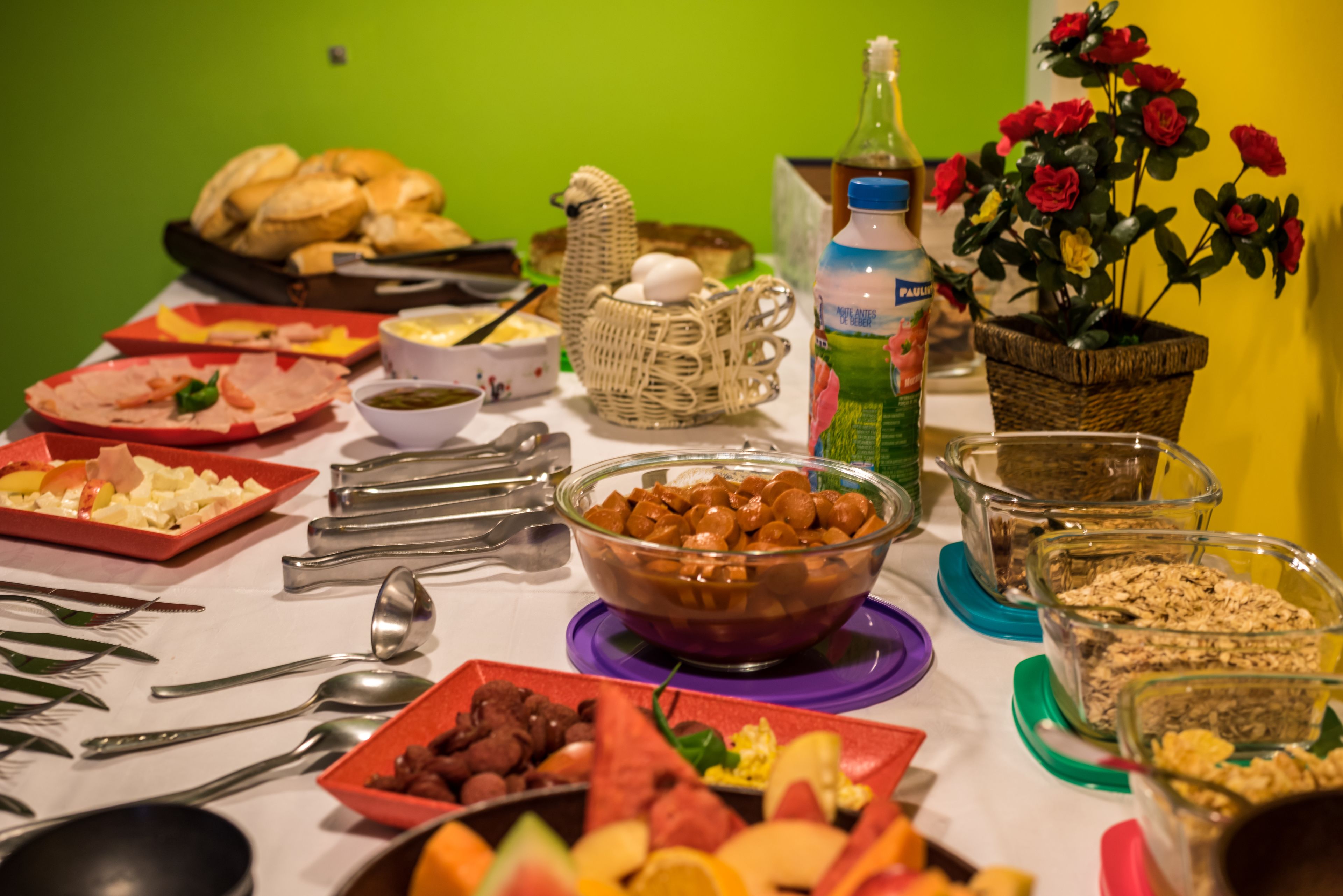 Uma mesa com diversos alimentos e utensílios, incluindo pão, frutas e uma tigela de nozes.