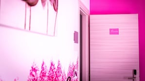 Um quarto com parede rosa, porta com a inscrição "Fucsia" e teto com um desenho floral.