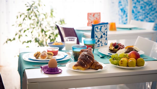 Mesa de café da manhã com croissants, frutas e bebidas.