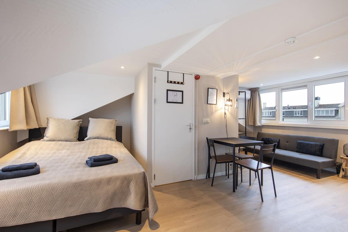Quarto de hotel moderno com cama, mesa de jantar e sofá.