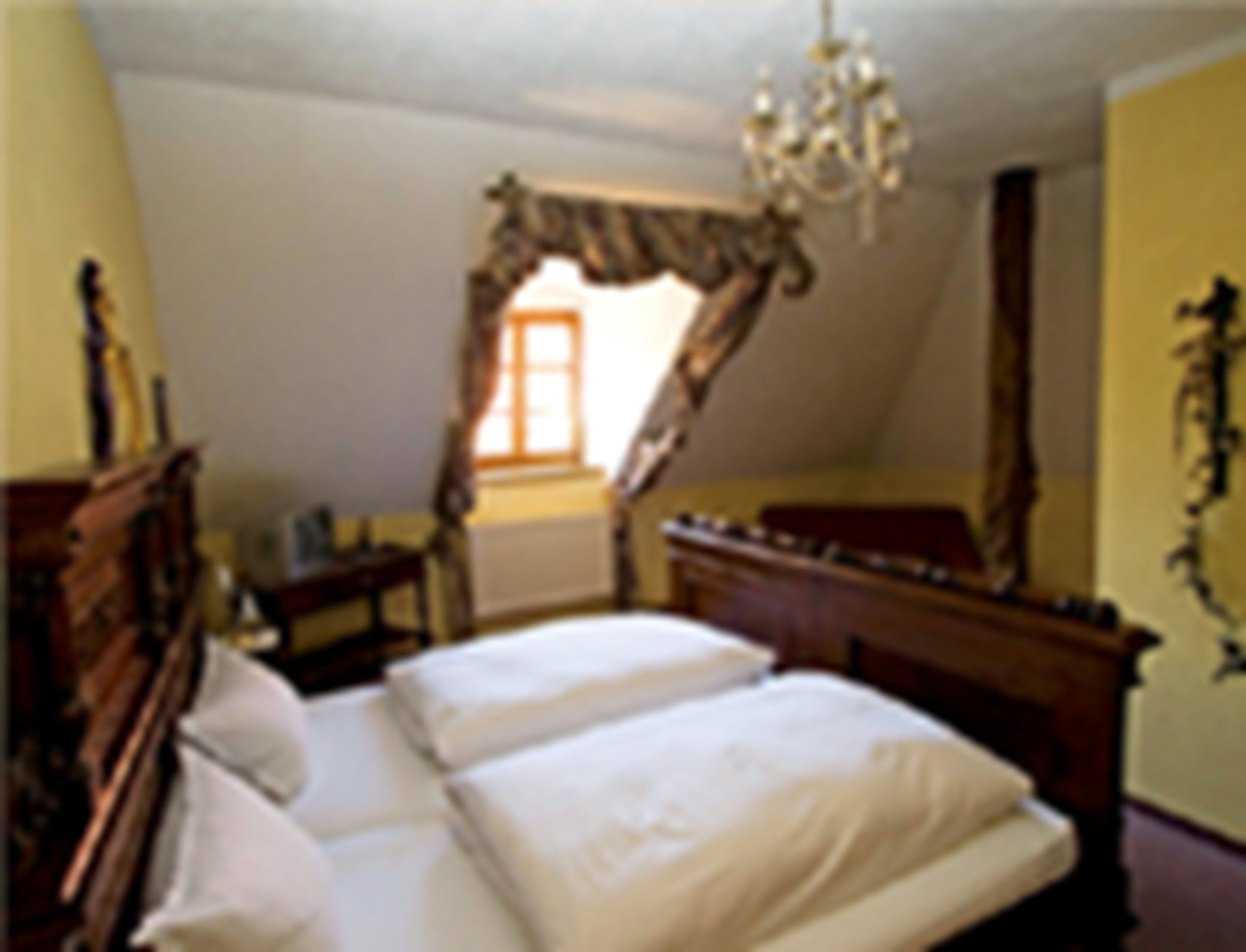 Quarto com uma cama grande, cômoda de madeira e um lustre.