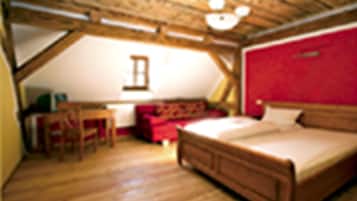 Quarto com teto de madeira, parede vermelha, cama, escrivaninha e uma cadeira.