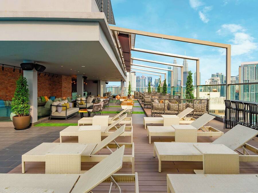 Um terraço com espreguiçadeiras, piscina e vista para a cidade.