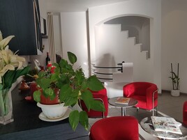 Uma sala de estar moderna com cadeiras vermelhas, um sofá branco e uma planta em vaso.