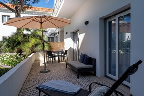 Um pátio com mesa, cadeiras, sofá e guarda-sol.