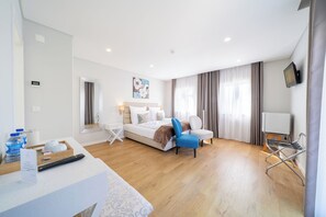 Quarto de hotel moderno com cama, escrivaninha, cadeira, televisão e janela com cortinas.