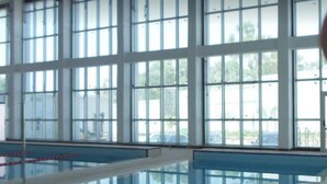 Uma grande piscina interior com várias pistas de natação e amplas janelas.