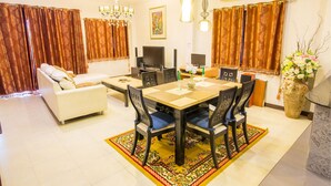 Uma sala de estar moderna com sofá, mesa de jantar, cadeiras, televisão e um vaso decorativo.