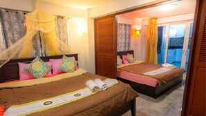 Quarto de hotel com duas camas, incluindo uma cama com dossel, e porta de correr para uma varanda.