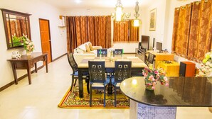 Uma área de refeições com uma mesa redonda, cadeiras, um sofá e um candelabro.