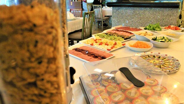 Mesa de buffet com diversos alimentos, incluindo carnes, vegetais e sobremesas.