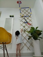 Criança escalando uma estrutura de escada fixada na parede, com um aro de basquete no topo.