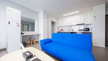 Um espaço compacto com cozinha compacta, um sofá, uma pequena mesa com um laptop e uma porta branca.