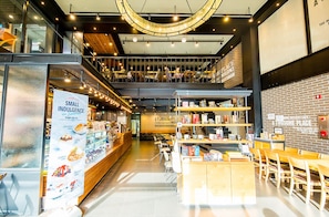 Um café moderno com um mezanino, móveis de madeira e diversas opções de assentos.