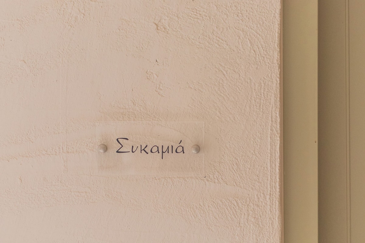 Paredes com uma placa de identificação que diz 'Евкатио' e uma porta à direita.