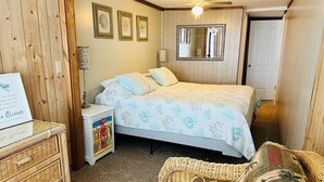 Quarto com cama, cômoda, cadeira, abajur e espelho.