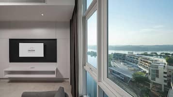 Quarto de hotel moderno com uma grande janela que oferece vista para a cidade e para o mar.