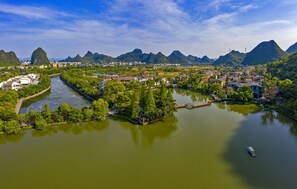Um rio com um barco, rodeado por vegetação e edifícios.