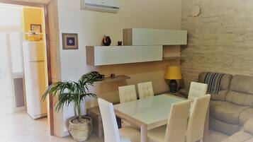 Uma sala de estar moderna com uma mesa de jantar, cadeiras, um sofá, um vaso de planta e um abajur.