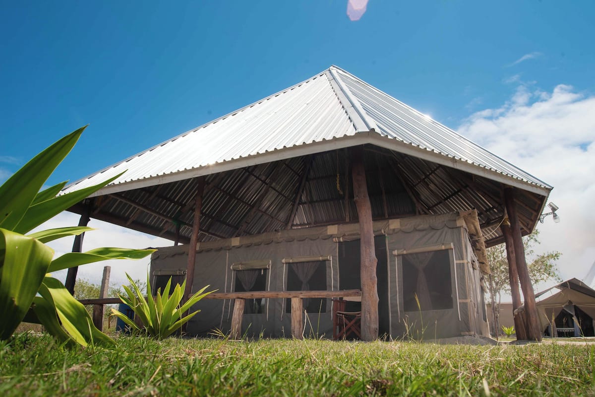 Uma construção rústica de um andar, com telhado de chapa de metal, vigas de madeira e um design simples e aberto.