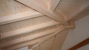 Quarto com vigas de madeira aparentes e teto inclinado.