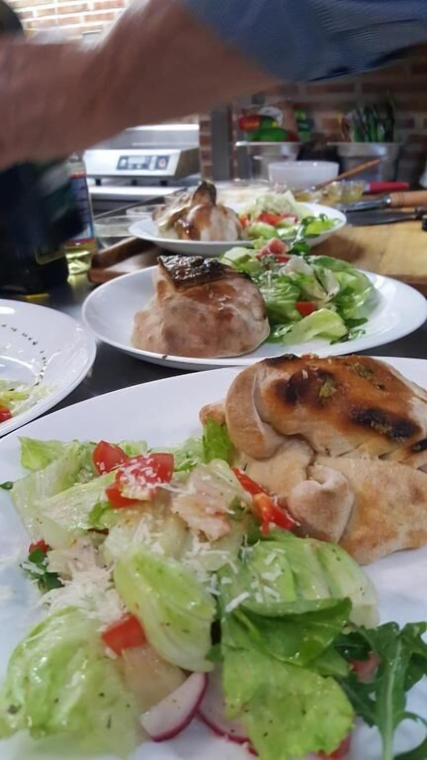 Mesa de jantar com pratos de comida, incluindo frango grelhado e saladas.