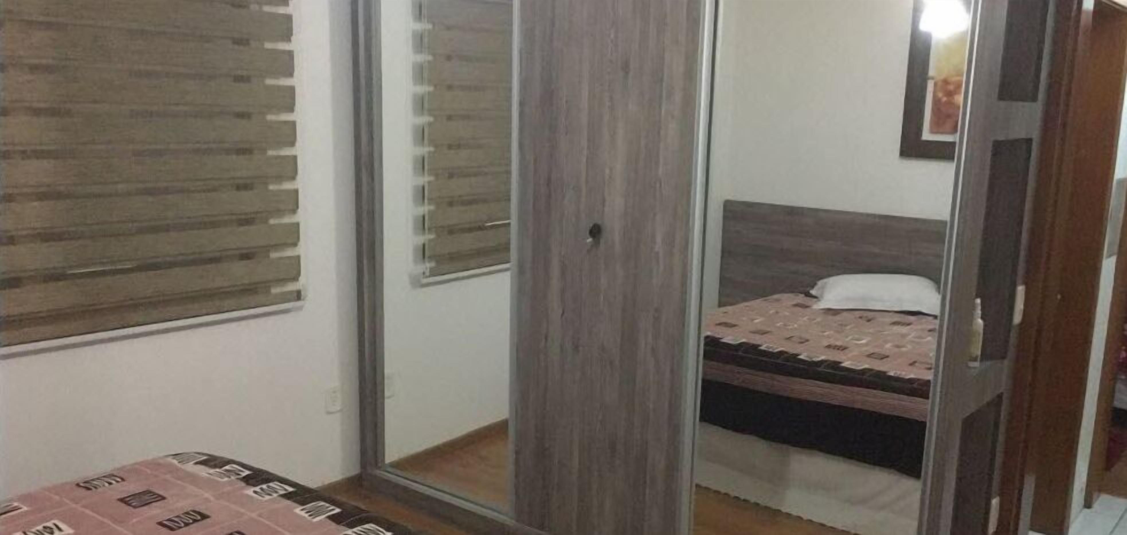 Quarto com cama, guarda-roupa e janela com persianas.