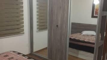 Quarto com cama, guarda-roupa e janela com persianas.