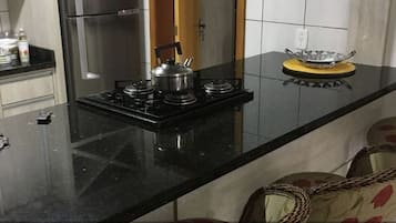 Cozinha com bancada preta, eletrodomésticos de aço inoxidável e uma bandeja amarela à direita.